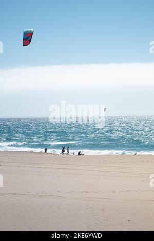 A vertical shot of the sunny Playa del Guincho with people parachuting ...