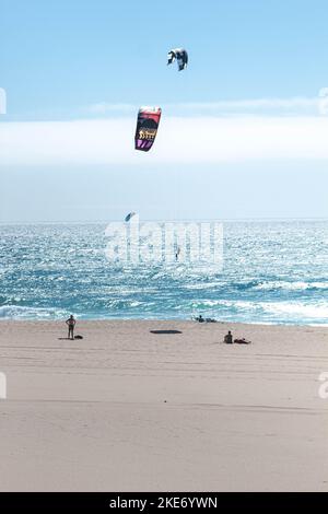 A vertical shot of the sunny Playa del Guincho with people parachuting ...