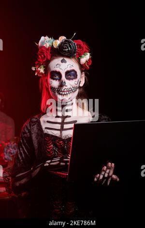 Woman in creepy santa muerte costume and wreath looking at camera on ...