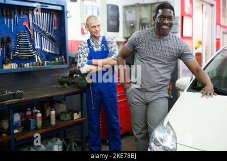 Portrait of satisfied male client with mechanician standing near her ...