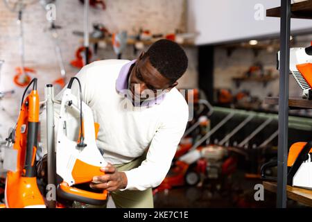African american man chooses chainsaw at garden tool store Stock Photo ...