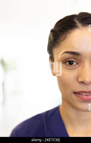 Portrait of half face of smiling biracial female healthcare worker in ...