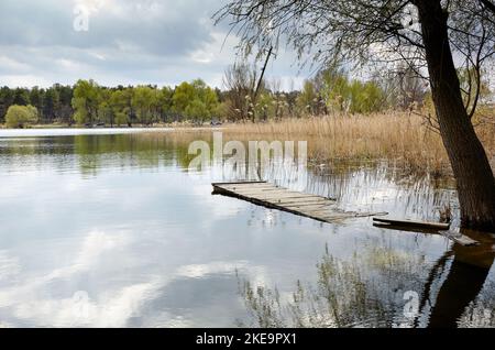 Flooded wooden pier on the river bank. Ripple on the water surface ...