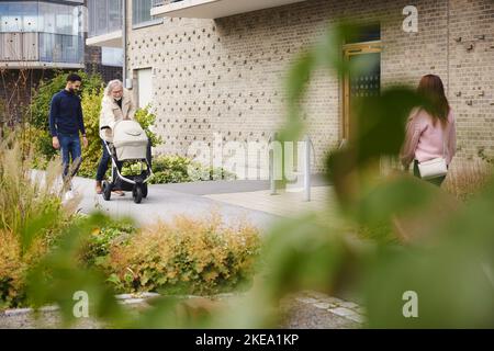 Men pushing pram in front of block of flats Stock Photo - Alamy