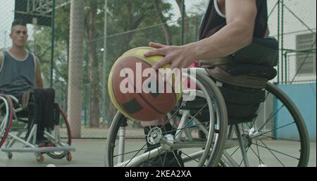 A paraplegic male athlete receiving ball from colleague outdoors. Two ...