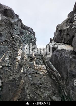 A vertical shot of rough rocky cliffs under a cloudy sky Stock Photo ...