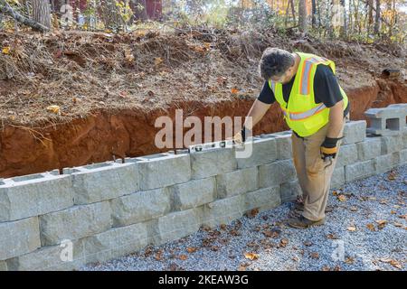 Man leveling tool building retaining concrete block wall with being ...