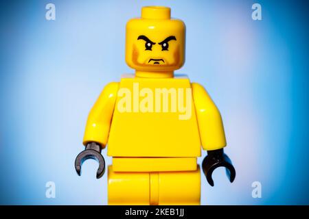 yellow lego figure with an angry face on a blue background. High ...