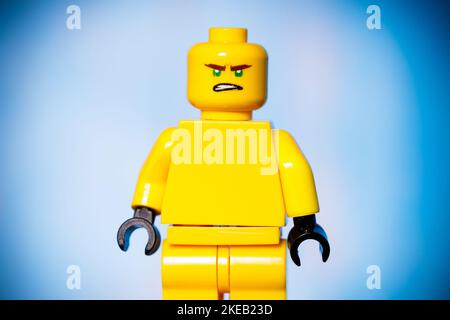 yellow lego figure with an angry face on a blue background. High ...