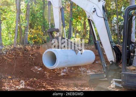 Worker use tractor lift up concrete sewage pipes from truck put down on ...