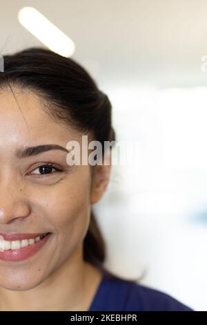 Vertical half face portrait of smiling biracial female healthcare ...