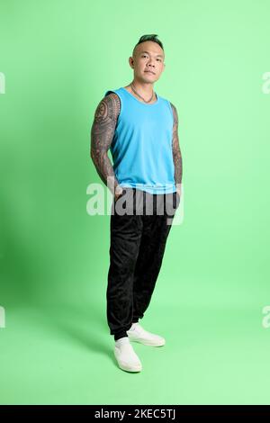The 40s adult Asian man with tattoo standing on the green background ...