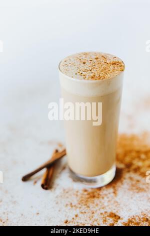 A closeup shot of a glass of a beige cinnamon mocha shake, sprinkled ...
