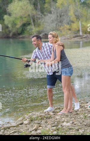 Lovely young couple fishing together by a lake at summer day Stock ...