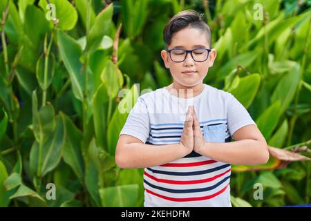 Adorable hispanic boy doing yoga exercise sitting on sofa at home Stock ...