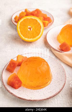 Papaya and orange jelly on gray concrete background and orange linen ...