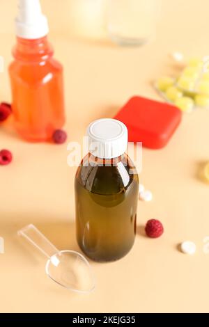 Cough syrup with spoon, raspberries and pills for sore throat on beige ...