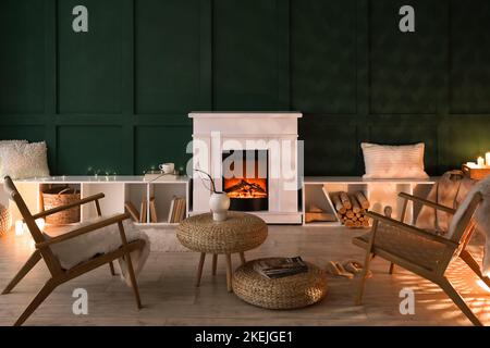 Shelving units with burning candles, books and frames near light wall ...