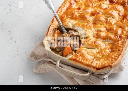 English beef steak pie with crispy puff pastry close-up in a baking ...