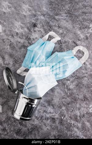 disposable surgical masks flying into or out of garbage can, concept of ...
