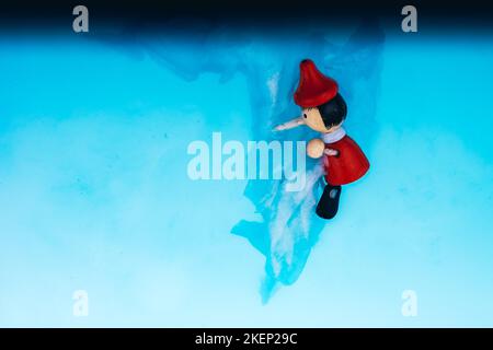 Wodden puppet Pinocchio on in blue water Stock Photo - Alamy