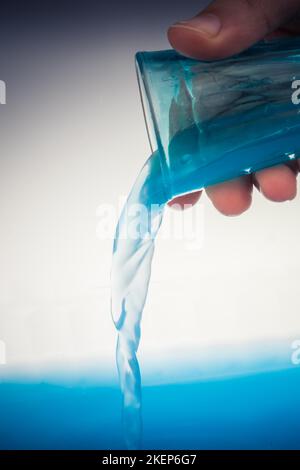 Water pouring down out of blue color glass in hand Stock Photo - Alamy