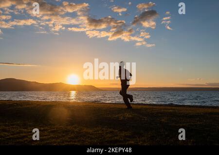 Man running by Lake Rotorua at sunset, Rotorua, New Zealand Stock Photo ...