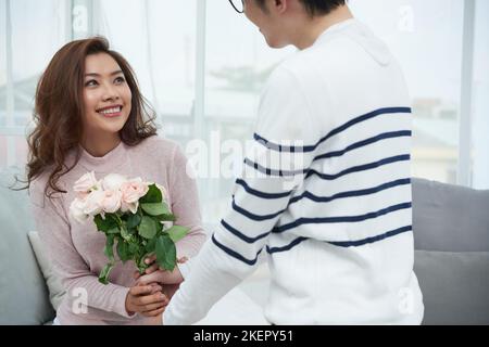 Young woman receiving bouquet of beautiful roses on brown background ...