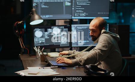 Male app developer answering landline phone call late at night, talking ...