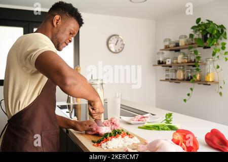 Young black man de-boning chicken to prepare a recipe Stock Photo - Alamy