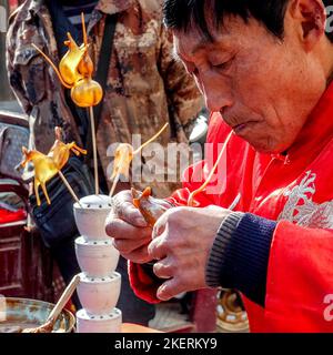Folk artist Ma Diankun is performing the Sugar Figure Blowing Art which is an intangible ...