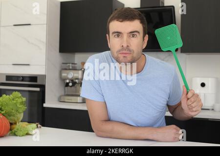 Man trying to catch a fly in his kitchen Stock Photo - Alamy