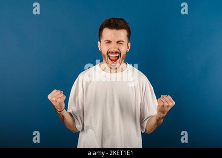 Caucasian man wearing white tee posing isolated over blue background ...