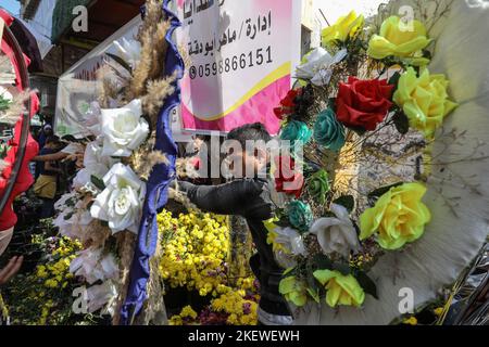 Palestinians in a flower shop distribute flowers to passers-by, to ...