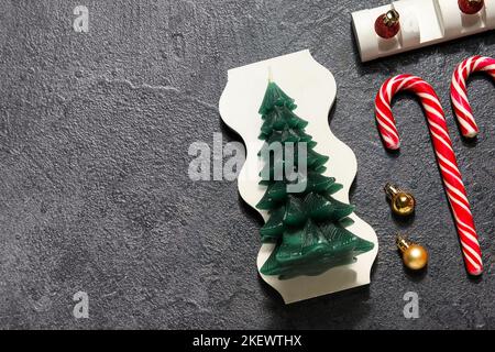 Christmas tree candle with podiums, candy canes and balls on dark ...
