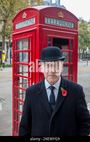 An old English gentleman with bowler hat and brolly strolls in the ...