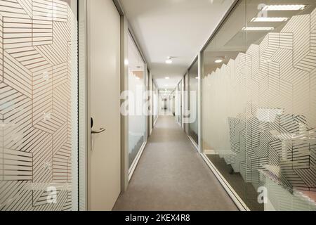 Long corridors of a coworking office with cubicles and glass partitions ...