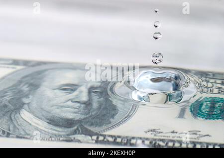 Drops of water and ripples with a hundred dollar bill growing economy ...