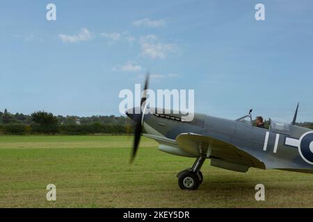 Man in 1940s RAF ground crew uniform with replica MK 2 Spitfire behind ...