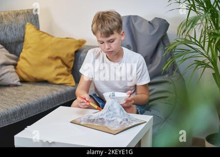 Child makes a creative project in the form of a mountain for homework ...
