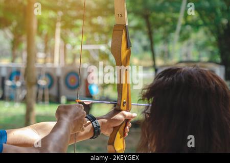 Hands of young man aims archery bow and arrow to colorful target in ...