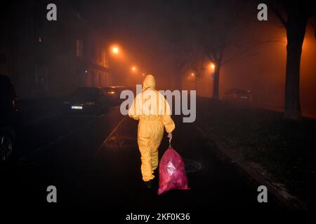 a person in yellow overall walking on the night smoggy road holding ...