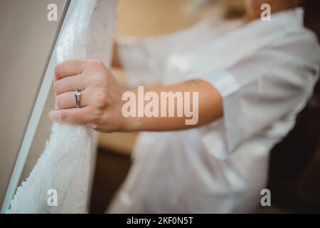 A selective focus of a bride's hand with a promise ring holding her ...