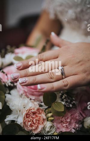 A selective focus of a bride's hand with a promise ring holding her ...