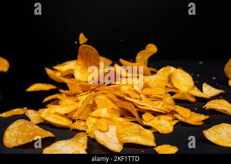 Black crispy potato chips set, on old dark wooden table, top view flat ...