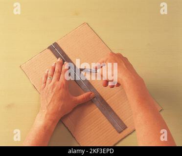 Drawing a line on the corrugated cardboard Stock Photo - Alamy