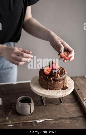 A vertical shot of a dripping chocolate cake with strawberries on a ...
