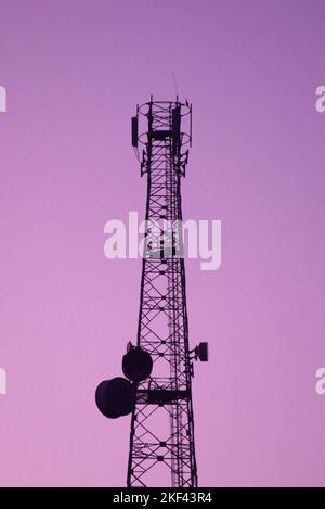 Vertical shot of a telecommunications tower against the blue cloudy sky ...