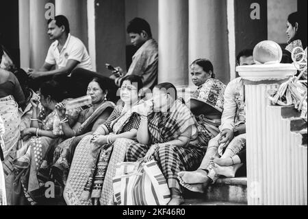 A grayscale of Indian women in traditional costumes filling buckets ...