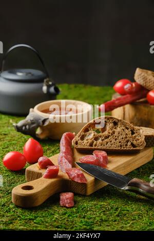 Snack on the moss with dried thin sausage, bread and tomatoes Stock ...